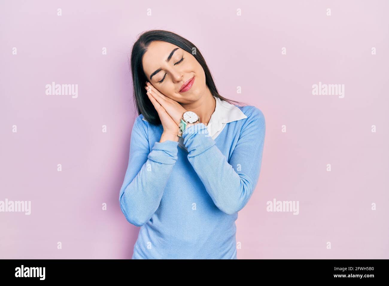 Beautiful woman with blue eyes standing over pink background sleeping ...