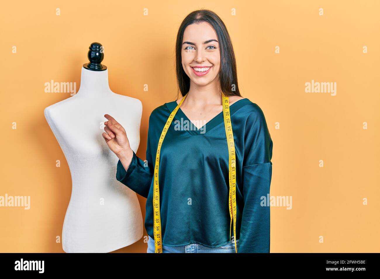 Beautiful woman with blue eyes standing by manikin smiling happy ...