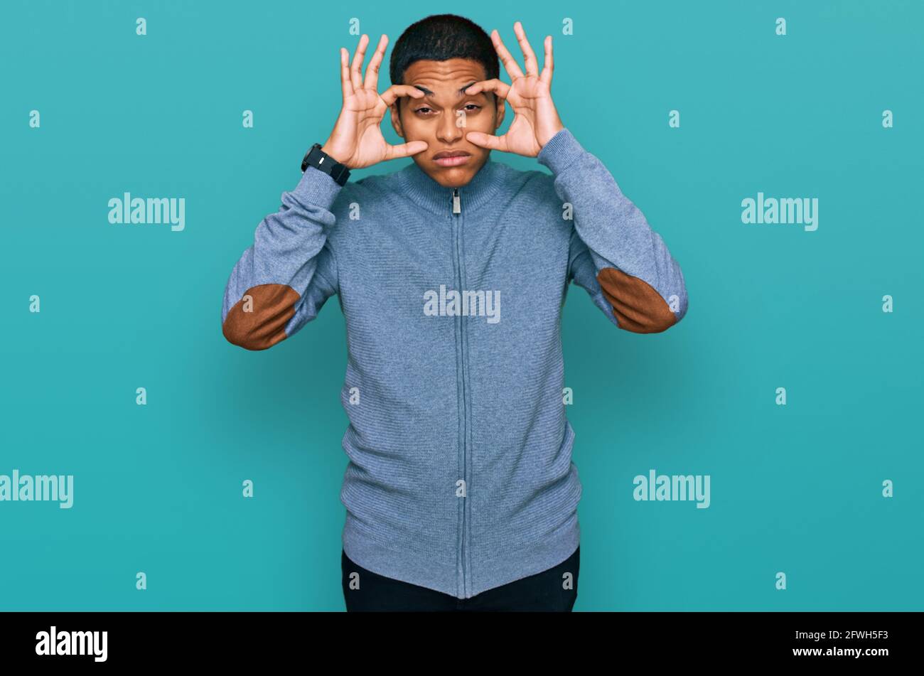 Young handsome hispanic man wearing casual sweatshirt trying to open ...