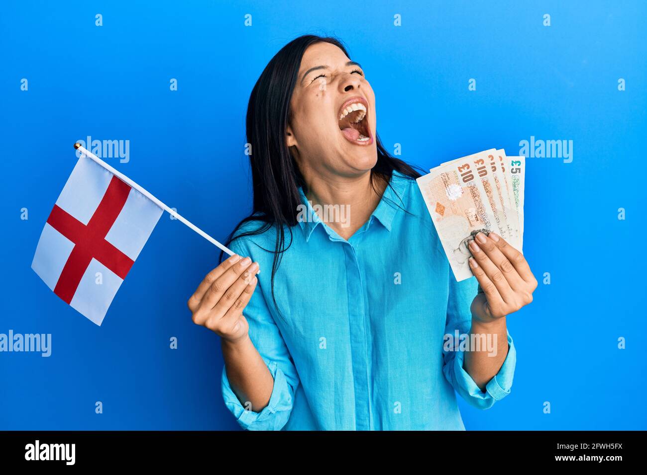 Young latin woman holding england flag and pounds banknotes angry and ...