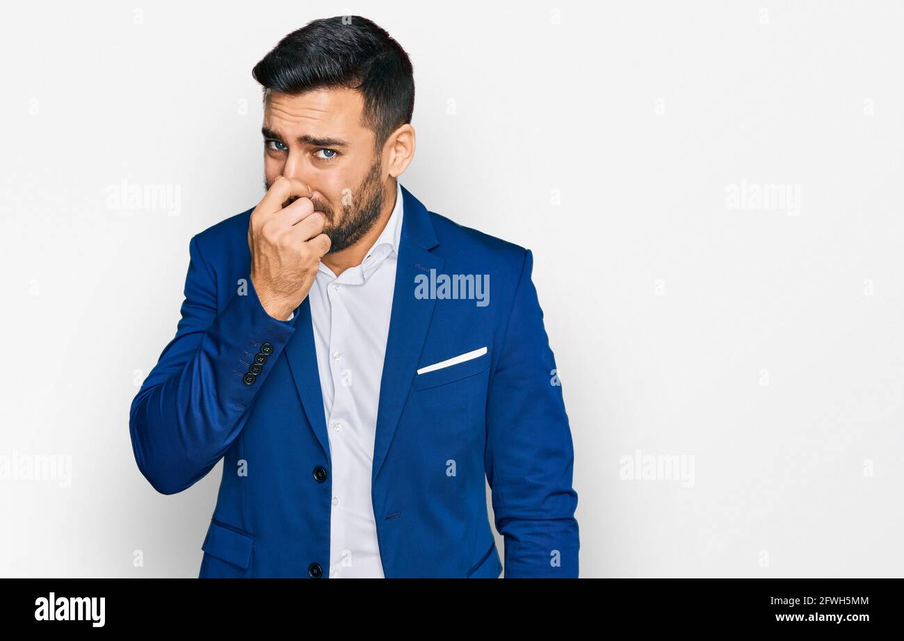 Young hispanic man wearing business jacket smelling something stinky ...