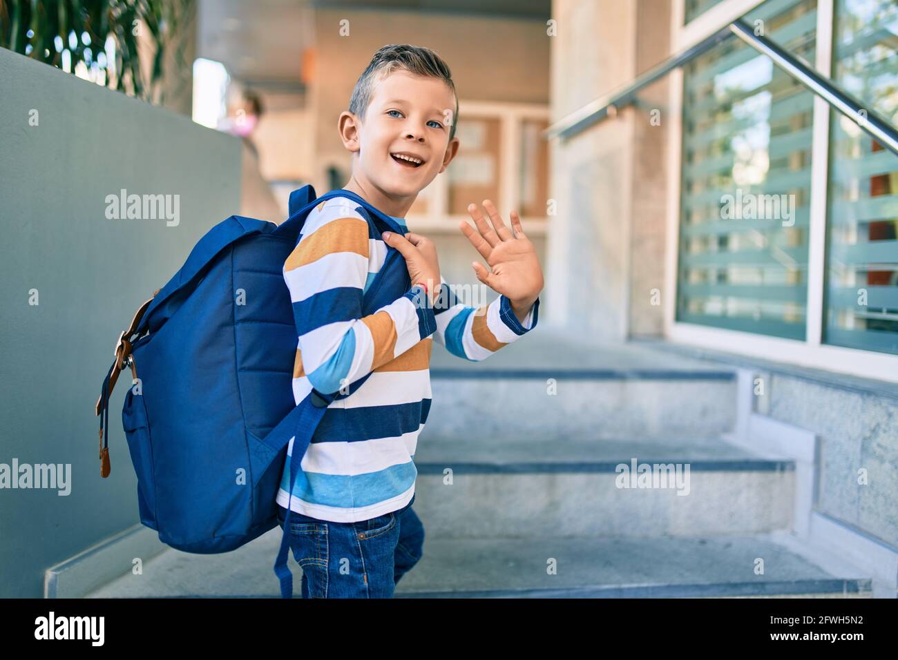 Adorable caucasian student boy smiling happy saying goodbye at the ...