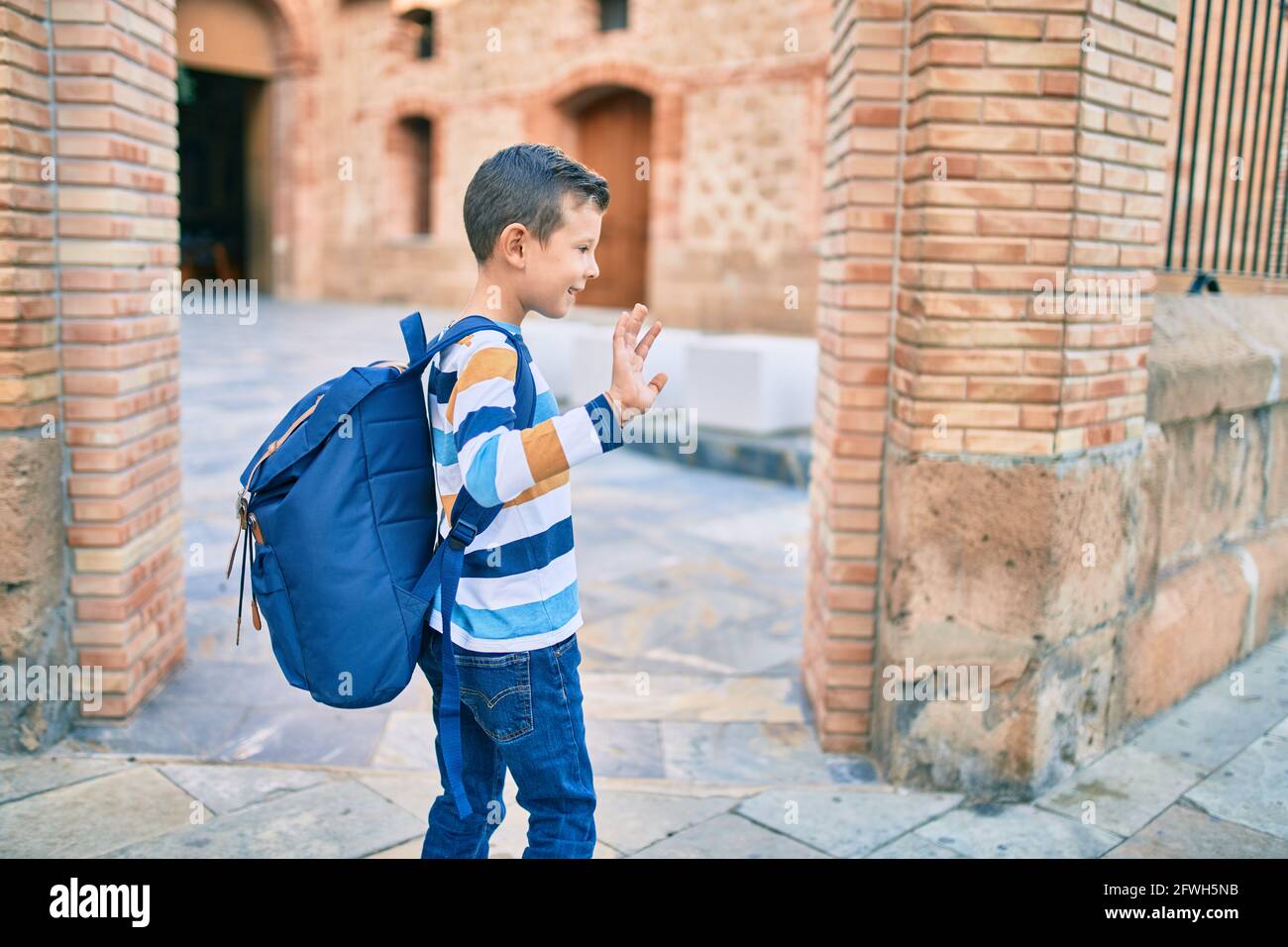 Adorable caucasian student boy smiling happy saying goodbye with hand ...