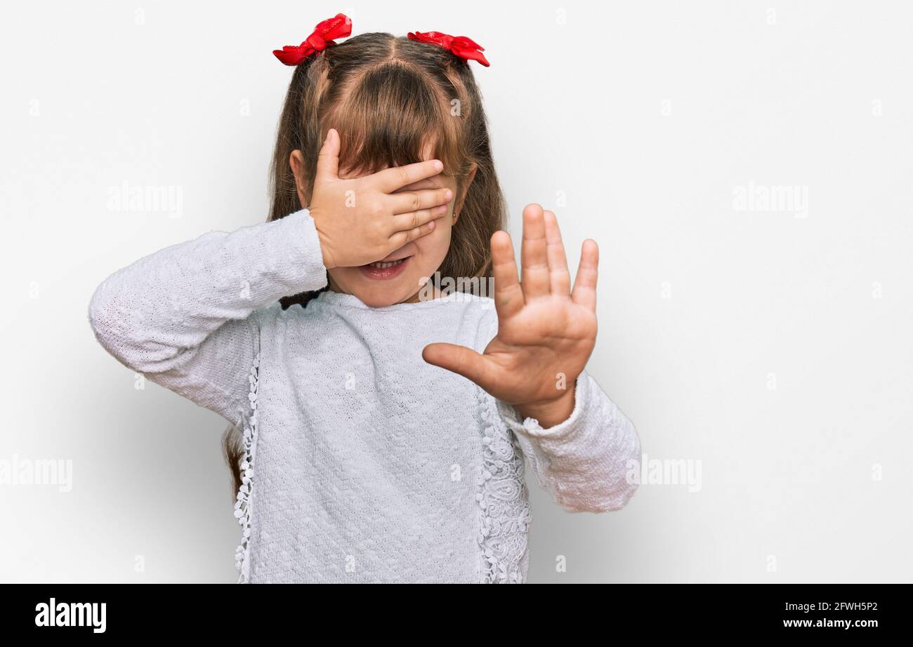 Little caucasian girl kid wearing casual clothes covering eyes with ...