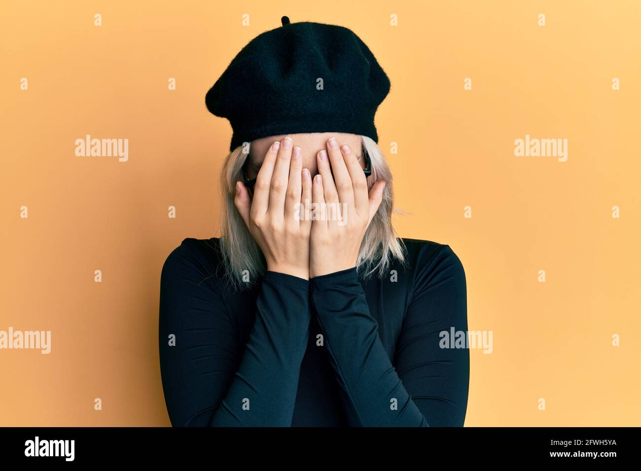 Young blonde girl wearing french look with beret with sad expression ...