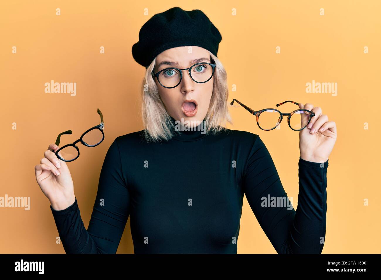 Young blonde girl wearing many glass over face in shock face, looking ...