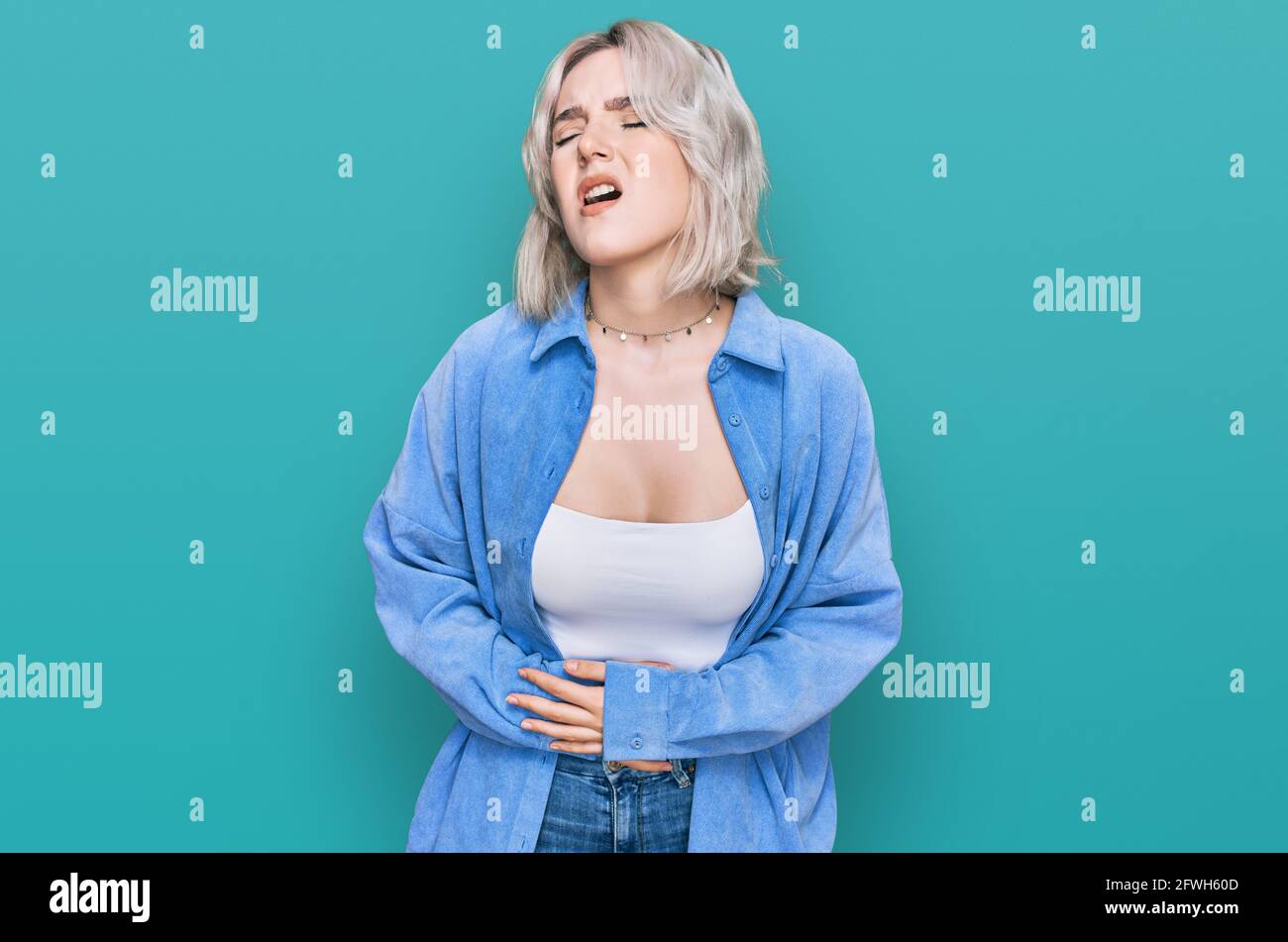 Young blonde girl wearing casual clothes with hand on stomach because ...