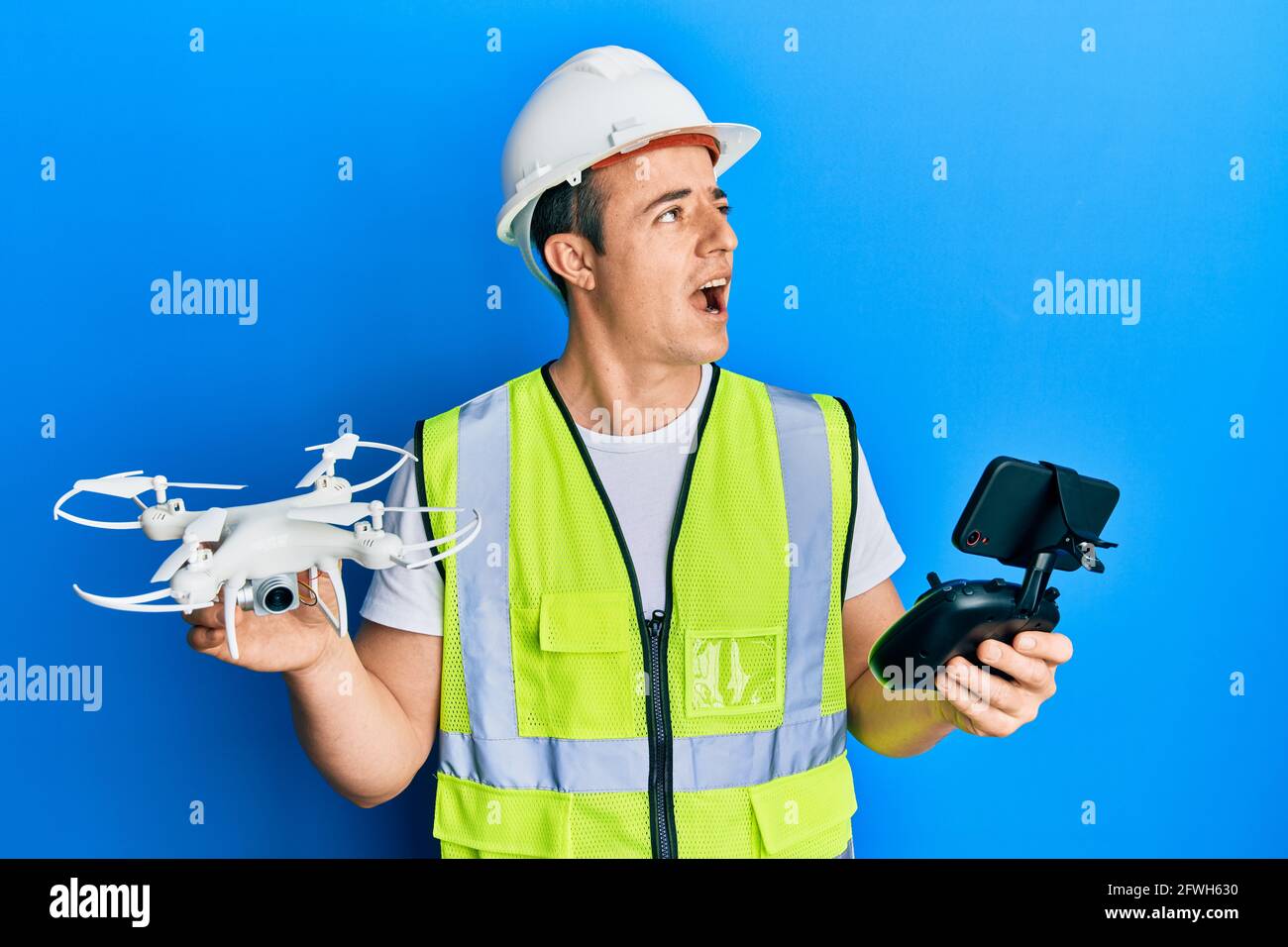 Handsome young man wearing safety hard using drone and control angry ...