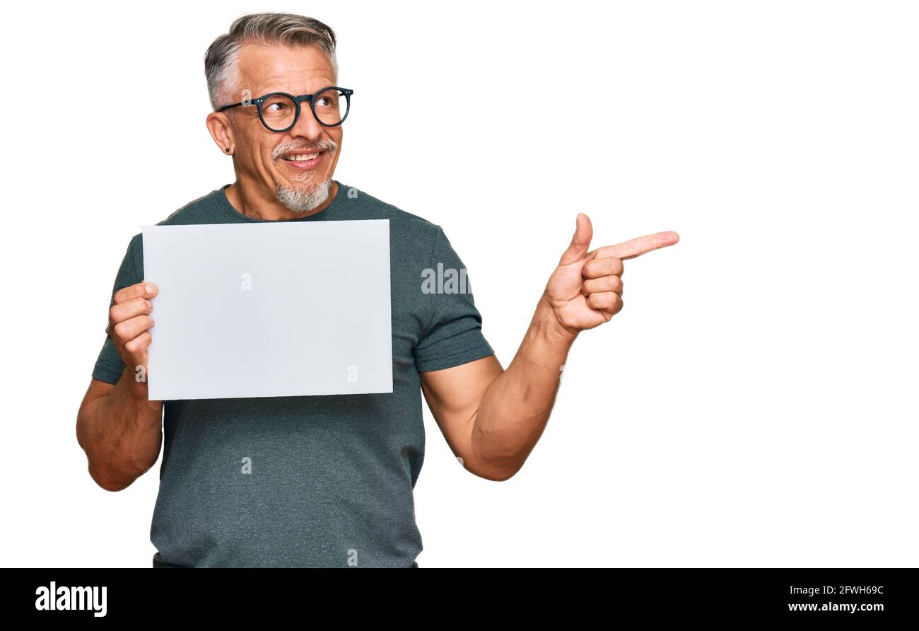 Middle age grey-haired man holding blank empty banner smiling happy ...