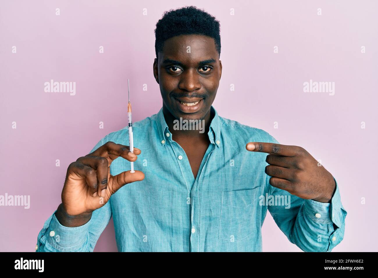 Handsome black man holding syringe smiling happy pointing with hand and finger Stock Photo - Alamy