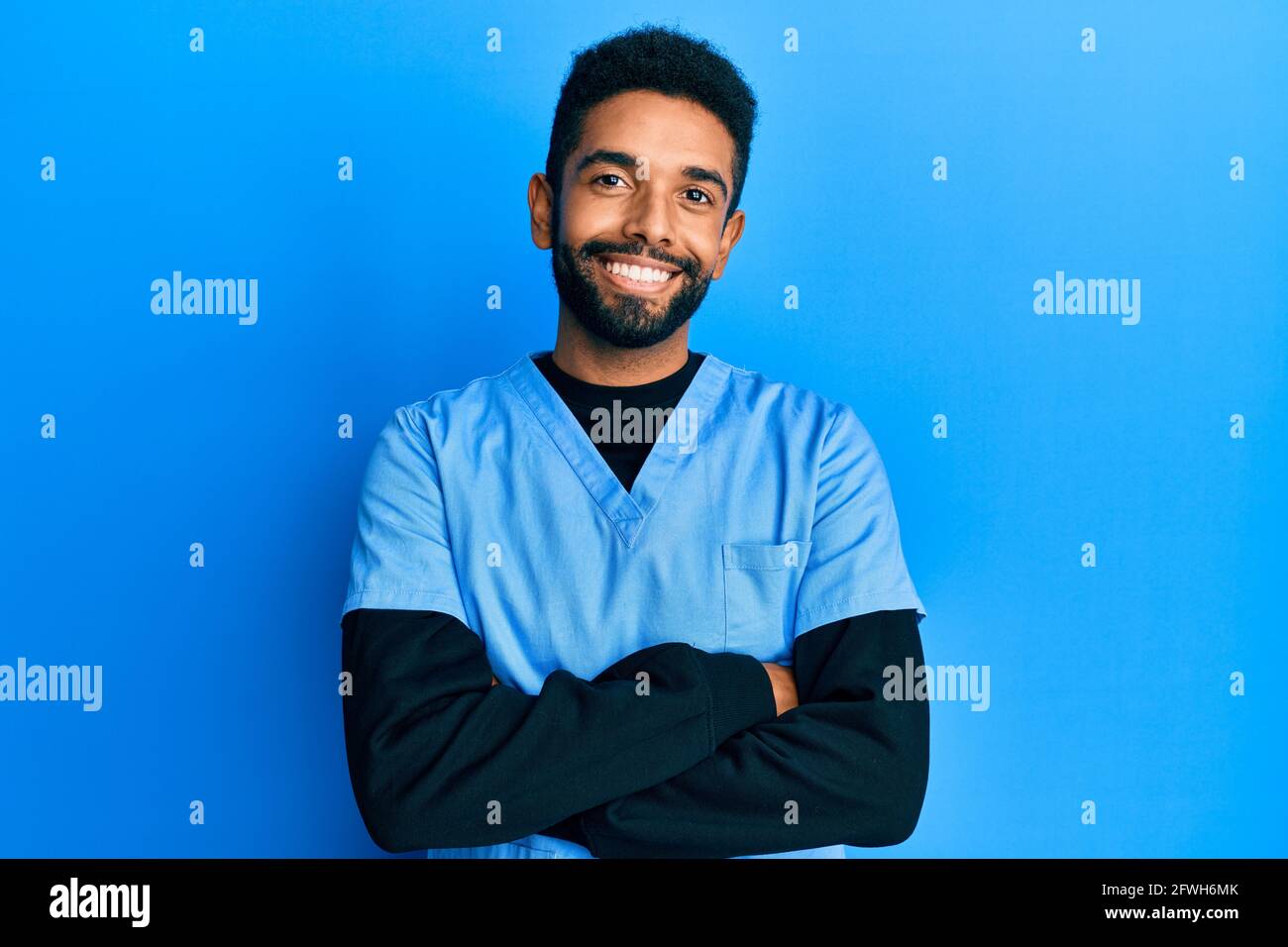 Handsome hispanic man with beard wearing blue male nurse uniform happy ...