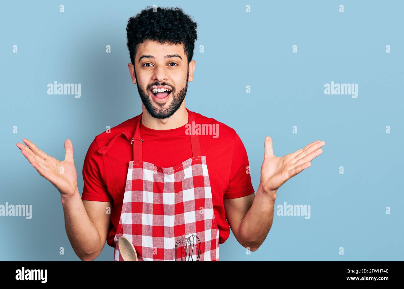 Young arab man with beard wearing cook apron celebrating crazy and ...