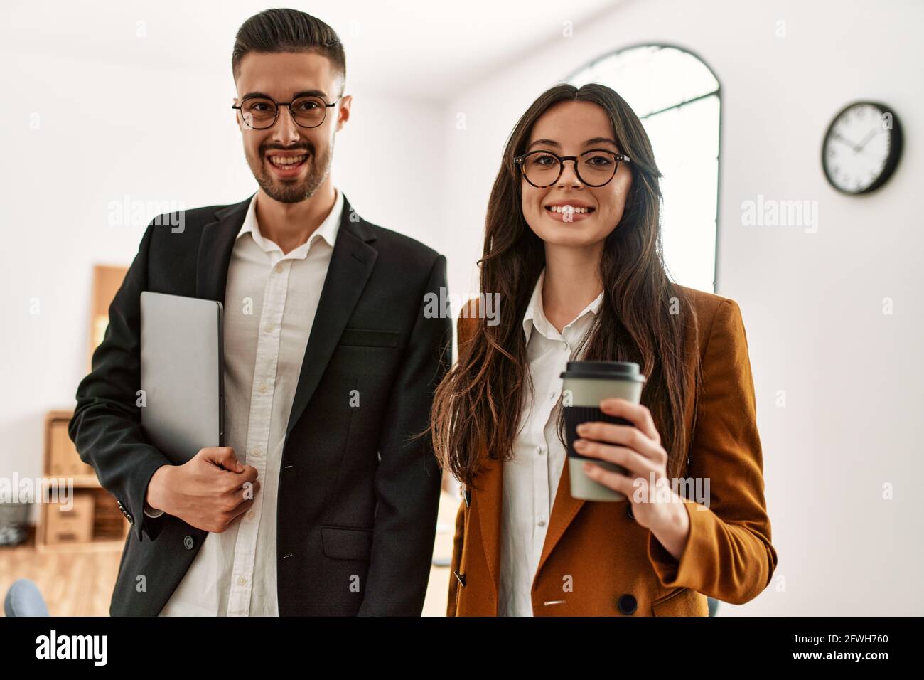Two hispanic business workers smiling happy drinking coffee at the ...