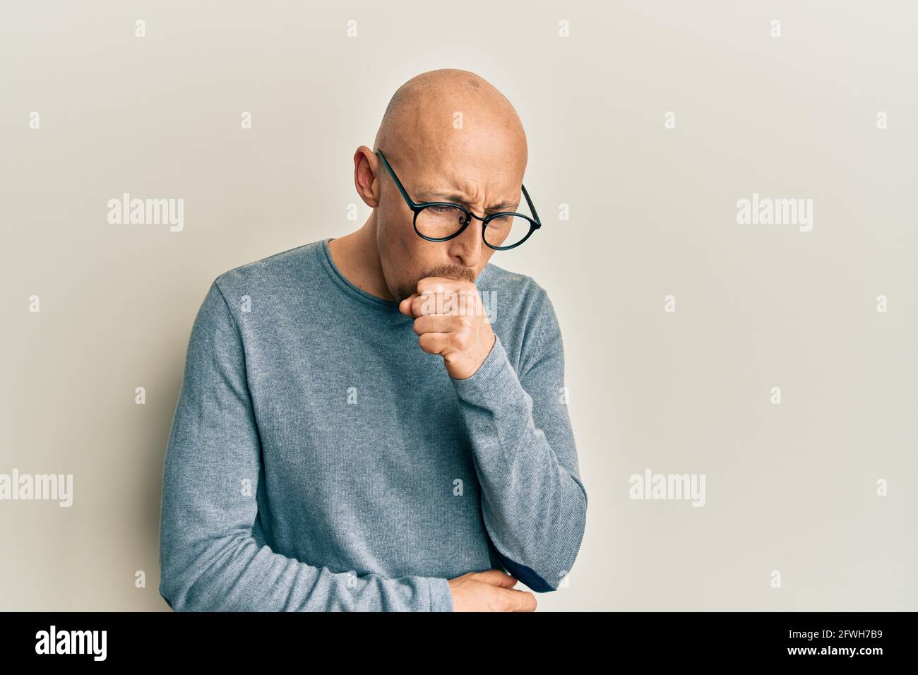 Bald man with beard wearing casual clothes and glasses feeling unwell ...