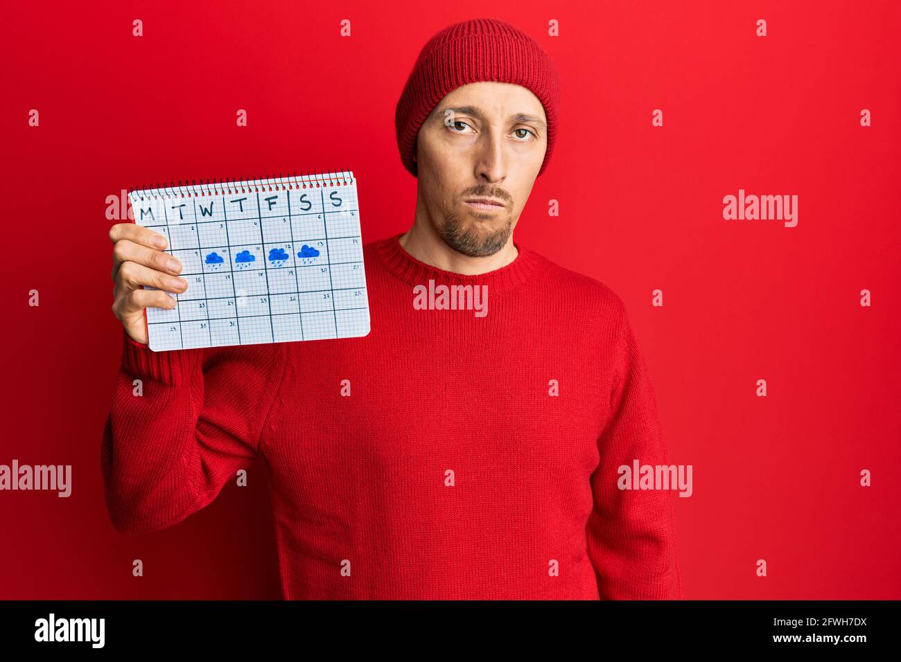 Bald man with beard holding rainy weather calendar thinking attitude ...