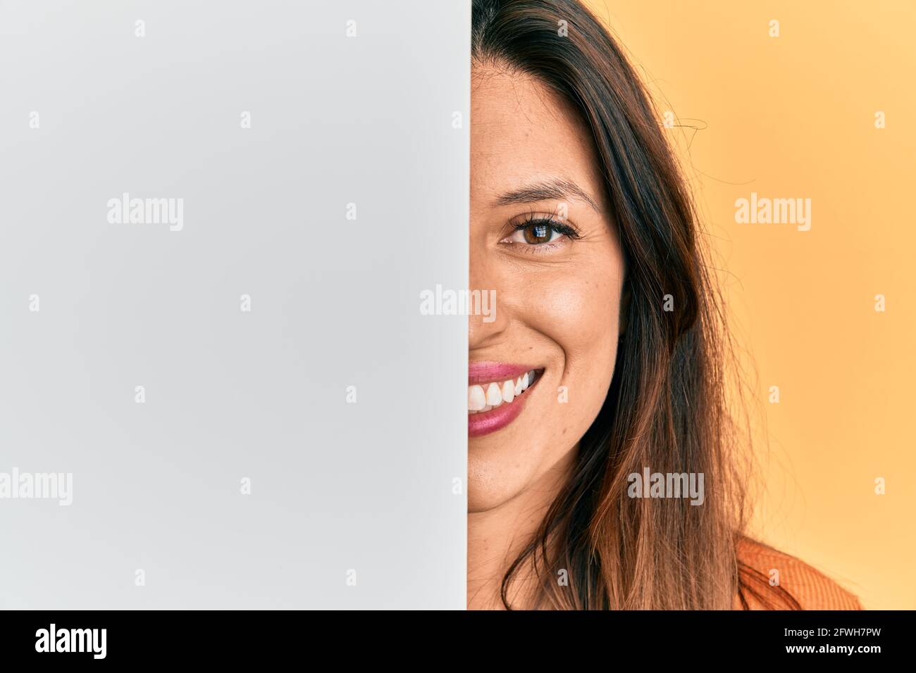 Beautiful hispanic woman holding blank empty banner covering half face ...