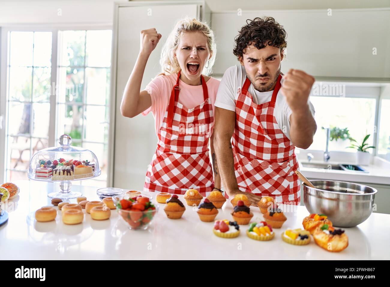 Couple of wife and husband cooking pastries at the kitchen angry and ...