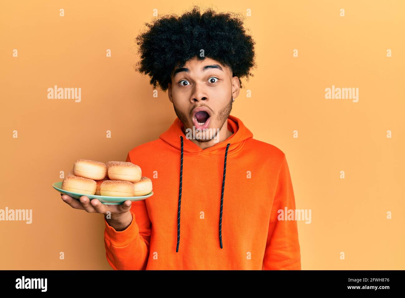 Young african american man with afro hair holding pile of tasty sugar ...