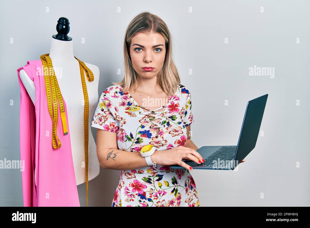 Beautiful caucasian woman dressmaker designer holding laptop depressed ...