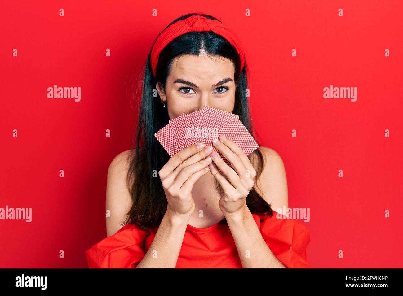 Young brunette woman covering face with cards smiling with a happy and ...
