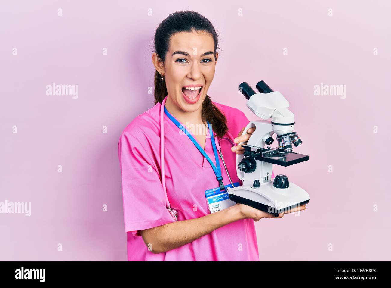 Young brunette woman holding microscope celebrating crazy and amazed ...