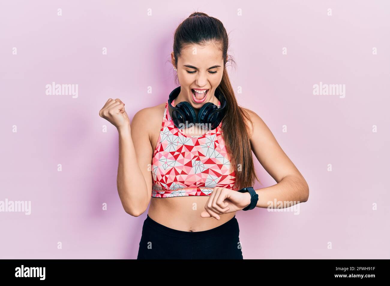 Young brunette teenager wearing gym clothes, using headphones and smart ...