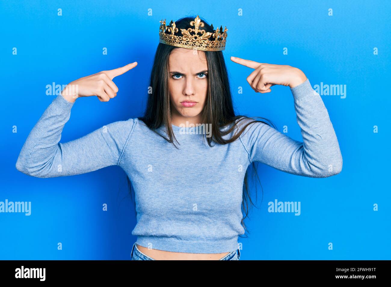 Young brunette teenager wearing princess crown skeptic and nervous ...