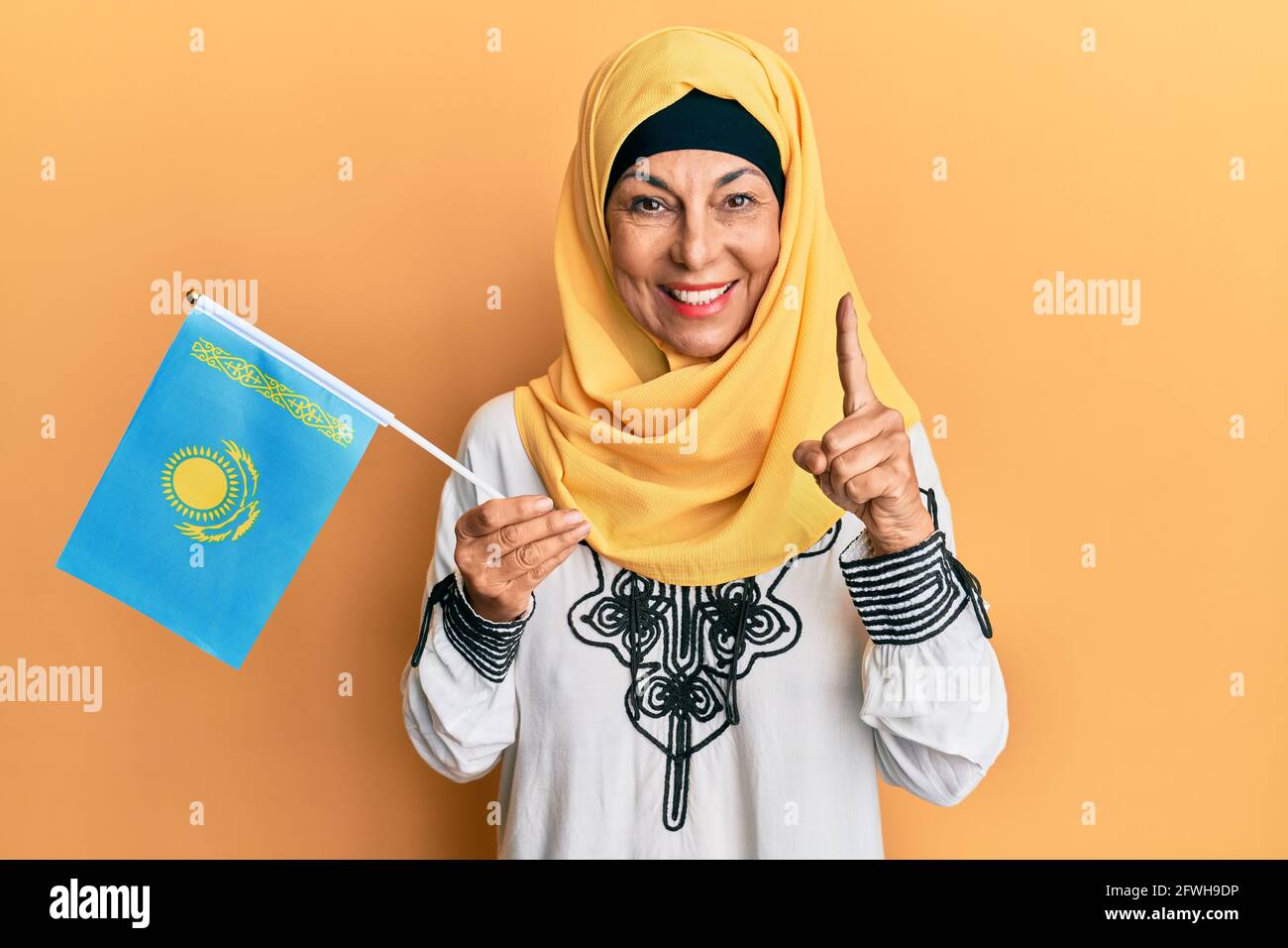 Middle age hispanic woman wearing hijab holding kazakhstan flag smiling ...