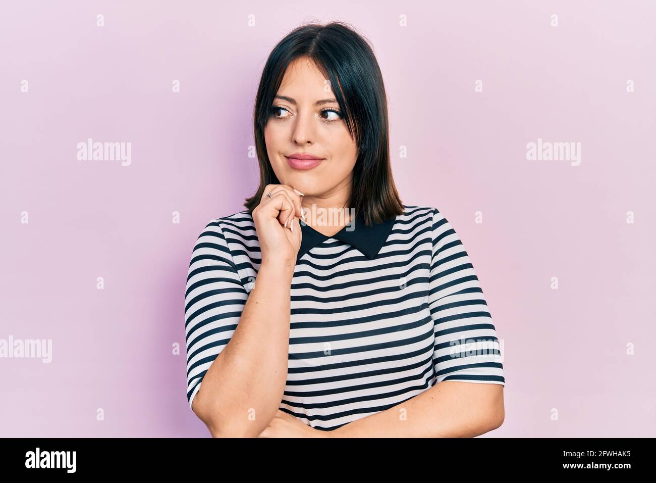 Young hispanic woman wearing casual clothes with hand on chin thinking ...