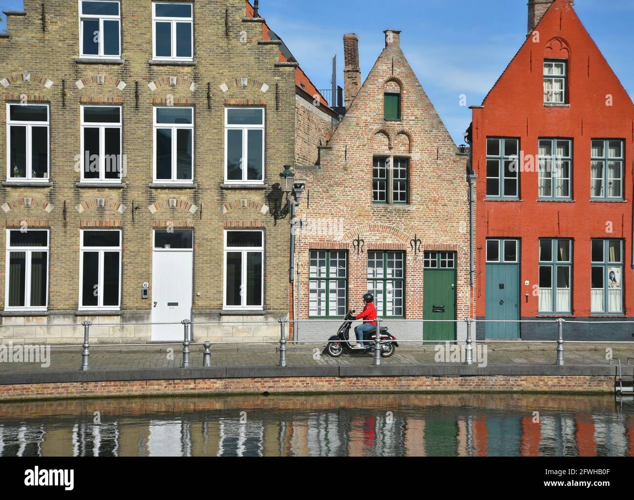 Scenic canal view with a vintage Vespa rider and Gothic Revival style ...