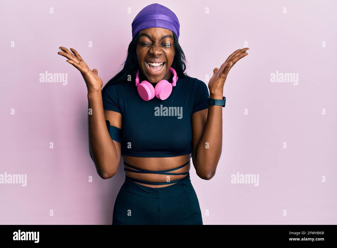 Young african american woman wearing gym clothes and using headphones ...