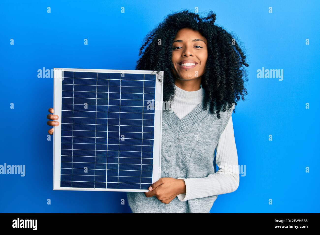 African american woman with afro hair holding photovoltaic solar panel ...