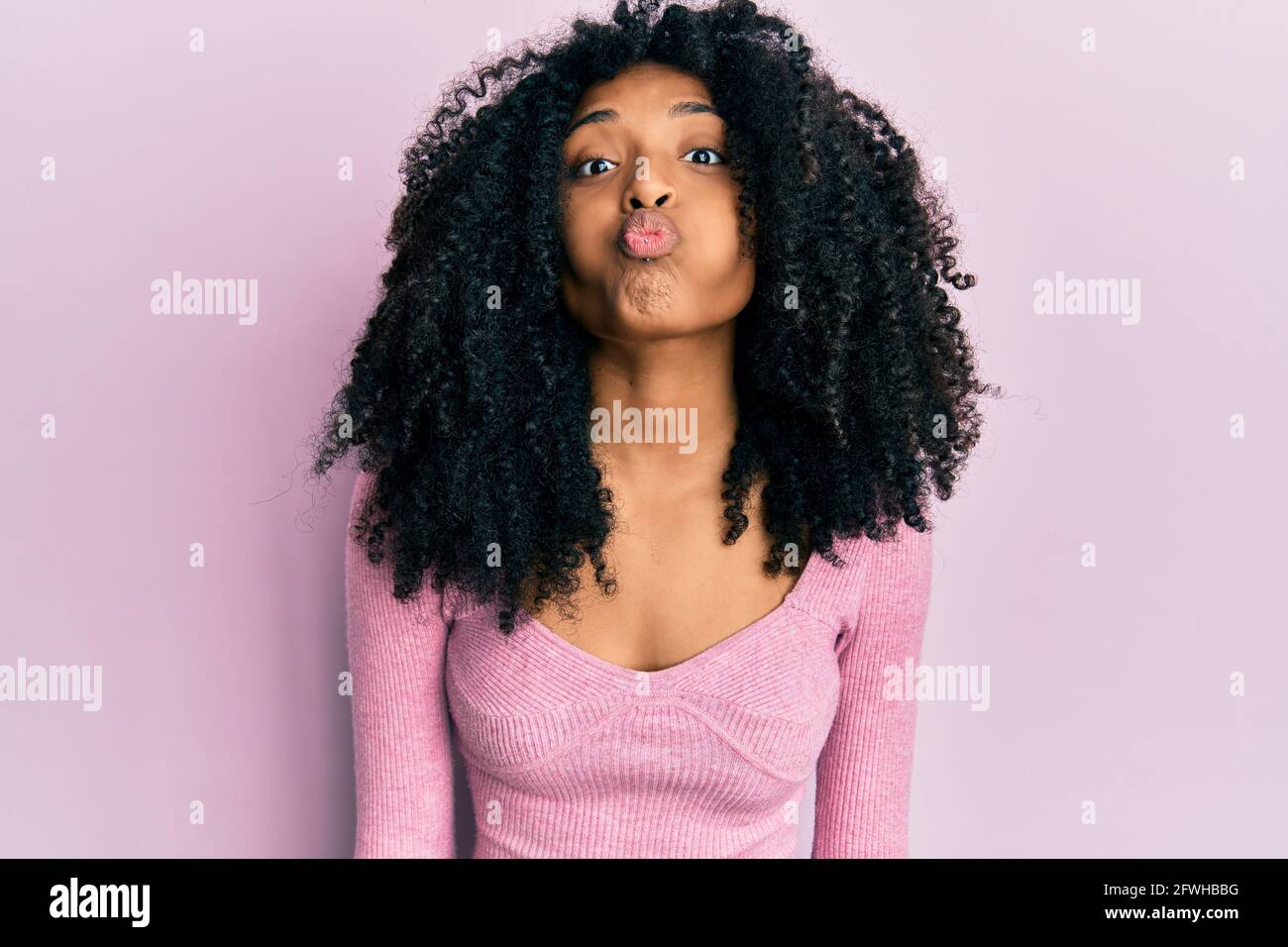 African american woman with afro hair wearing casual pink shirt puffing ...