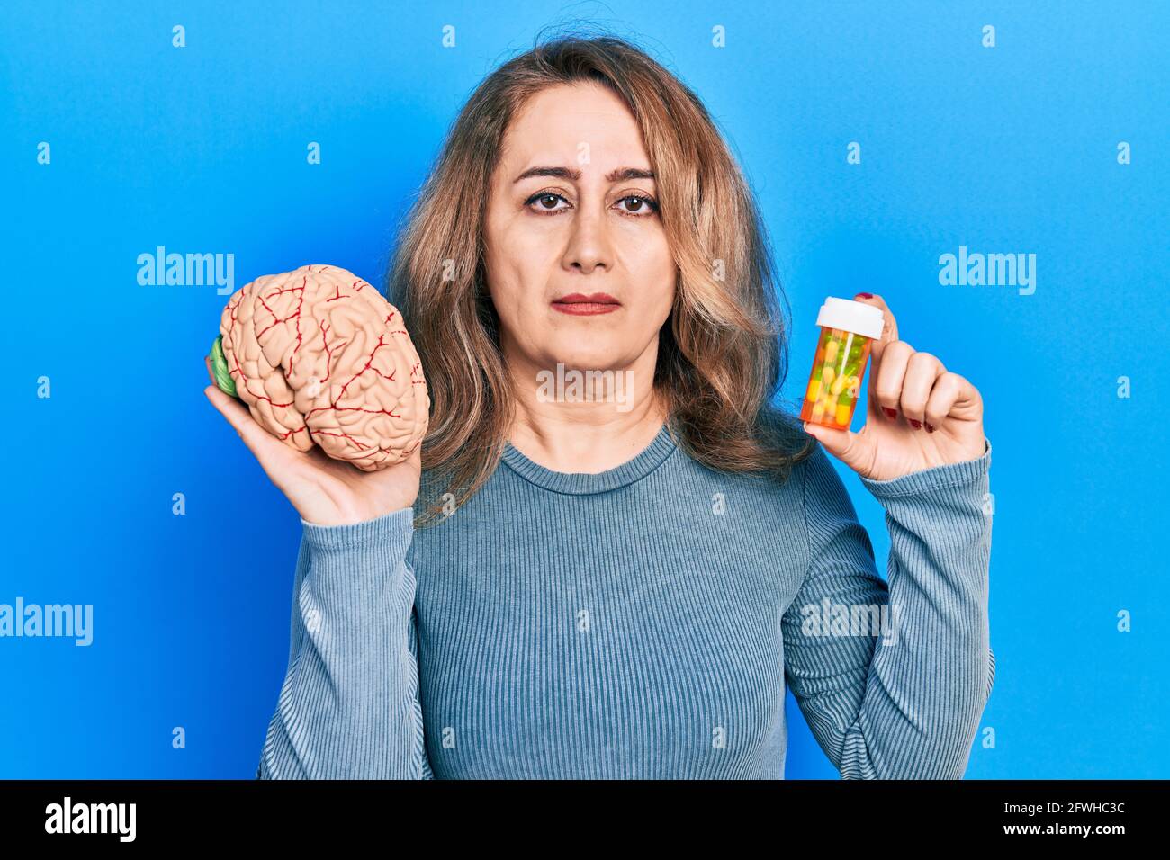 Middle age caucasian woman holding brain and pills as mental health ...