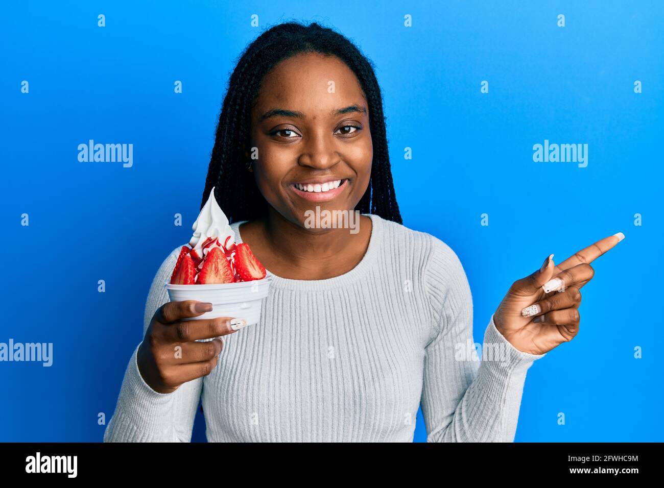 African american woman with braided hair eating strawberry ice cream ...