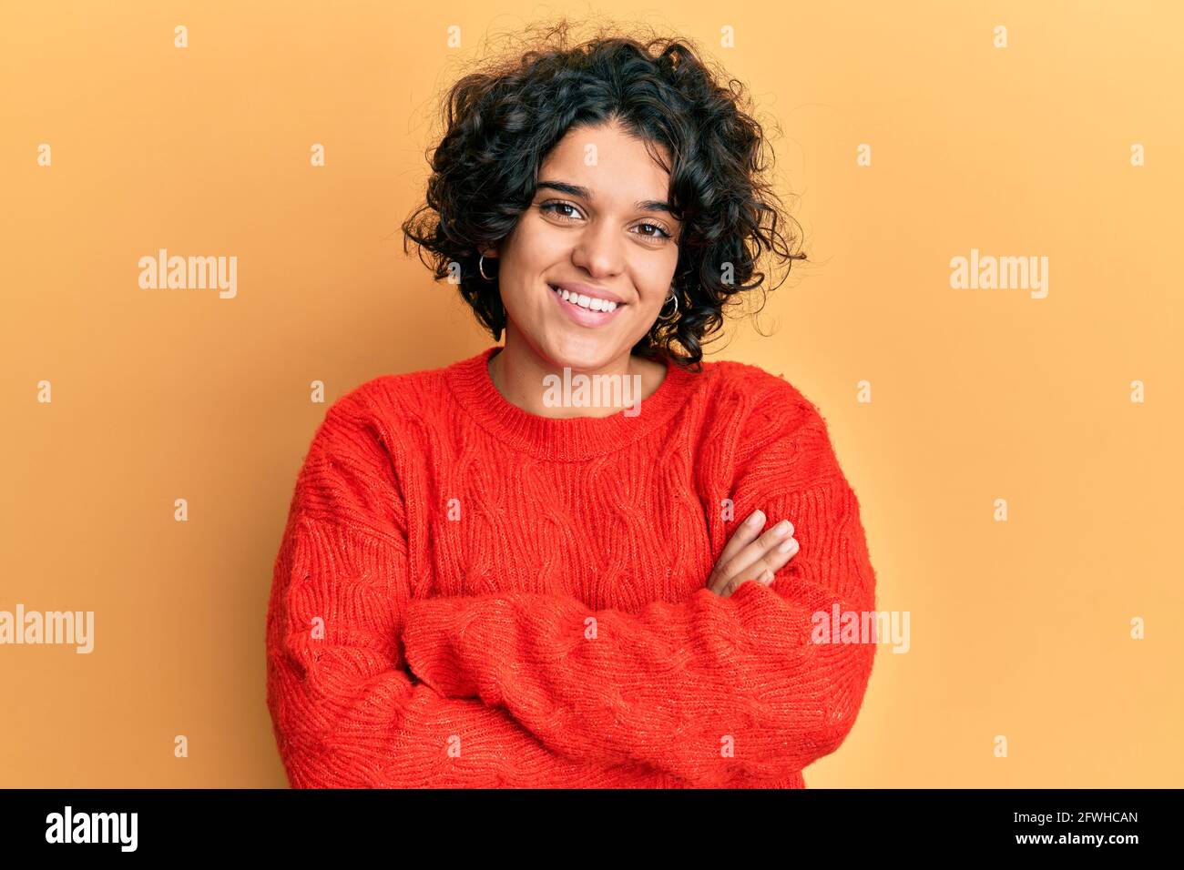 Young hispanic woman with curly hair wearing casual winter sweater ...