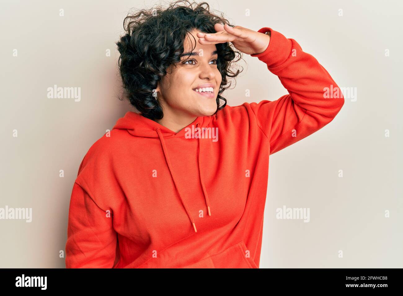 Young hispanic woman with curly hair wearing casual sweatshirt very ...