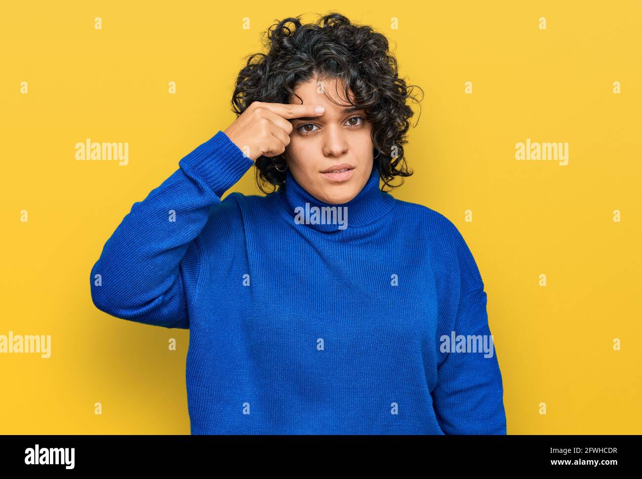 Young hispanic woman with curly hair wearing turtleneck sweater ...