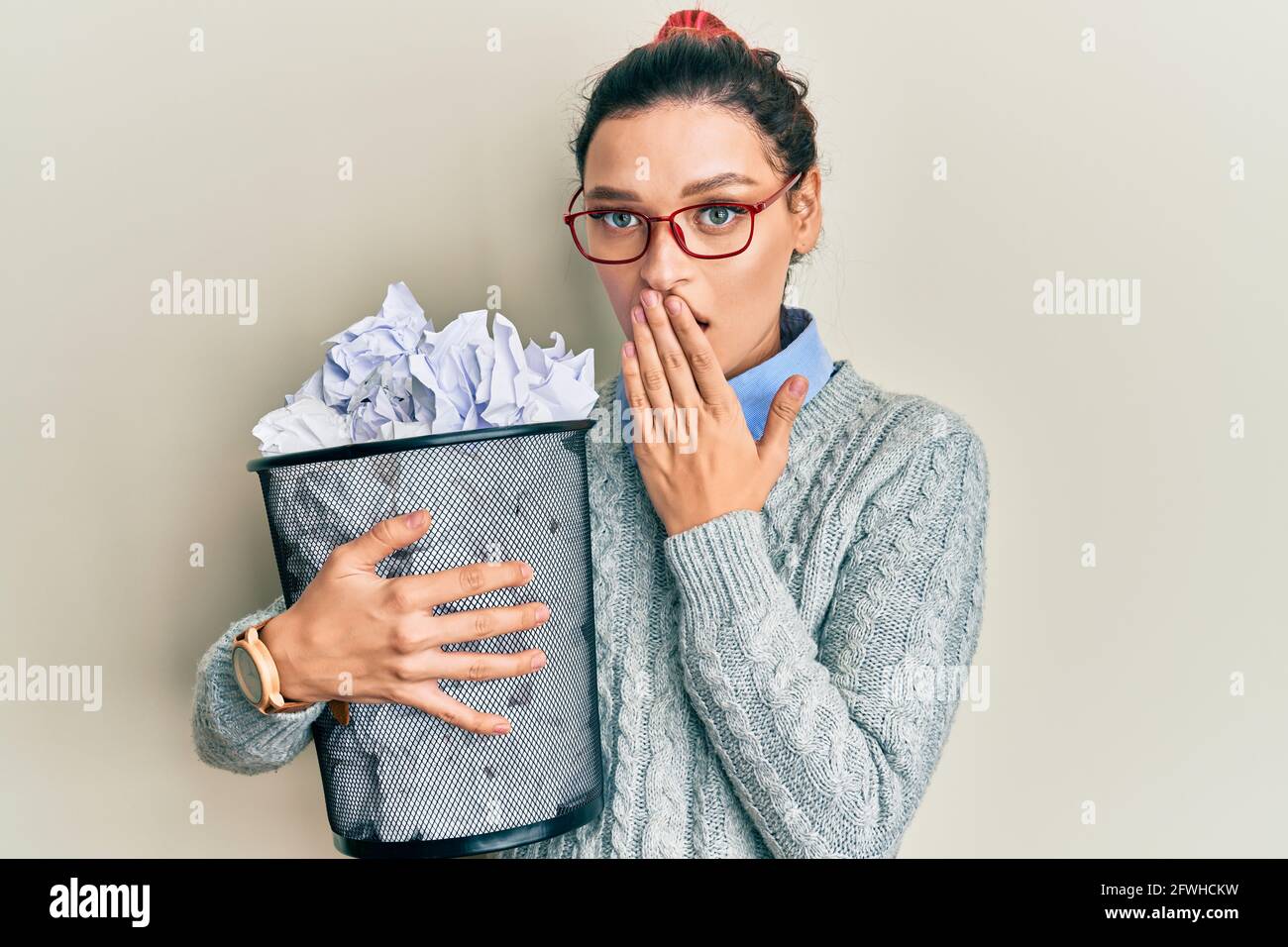 Young caucasian woman holding paper bin full of crumpled papers ...