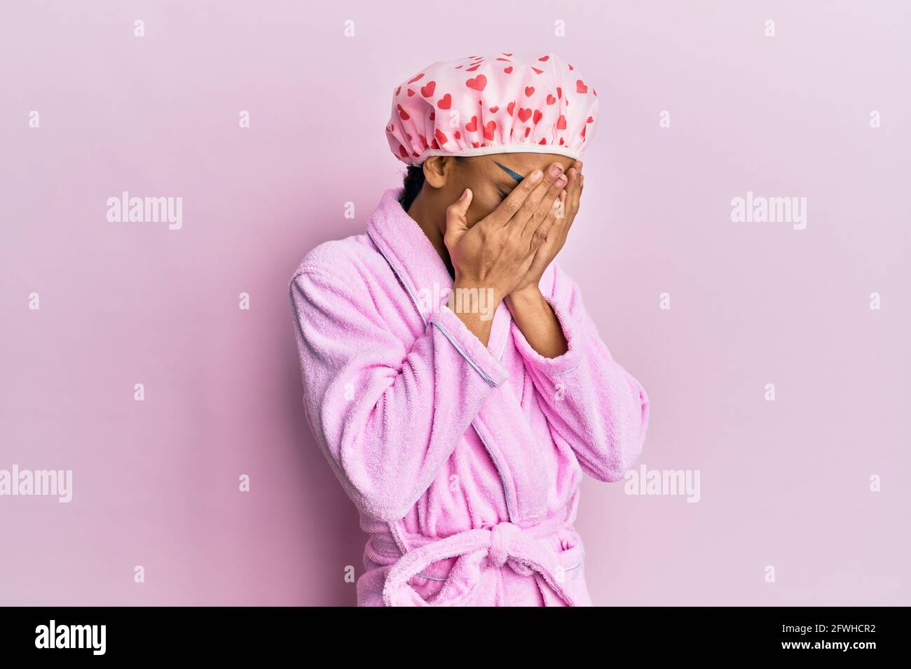 Hispanic man wearing make up wearing shower towel cap and bathrobe with ...