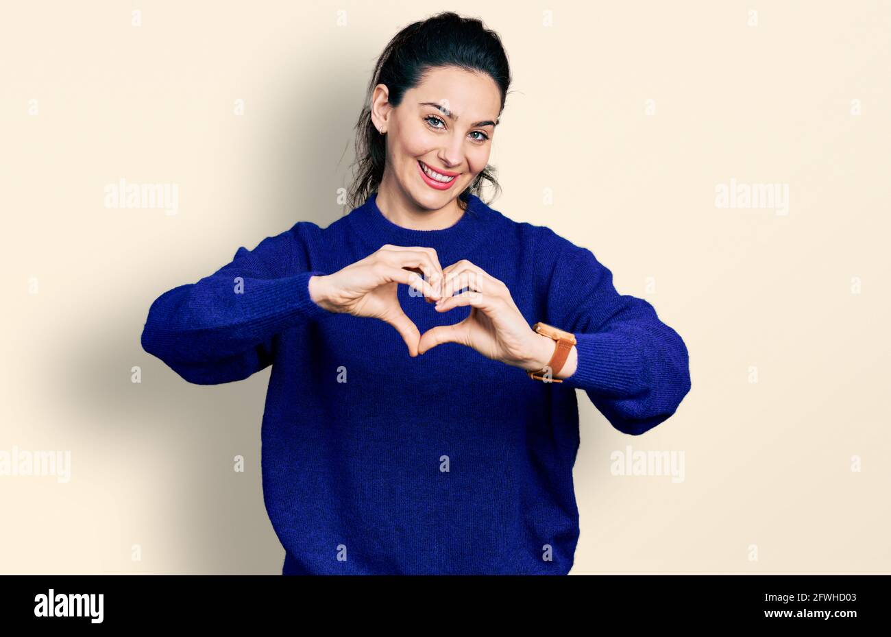 Young hispanic woman wearing casual clothes smiling in love doing heart ...
