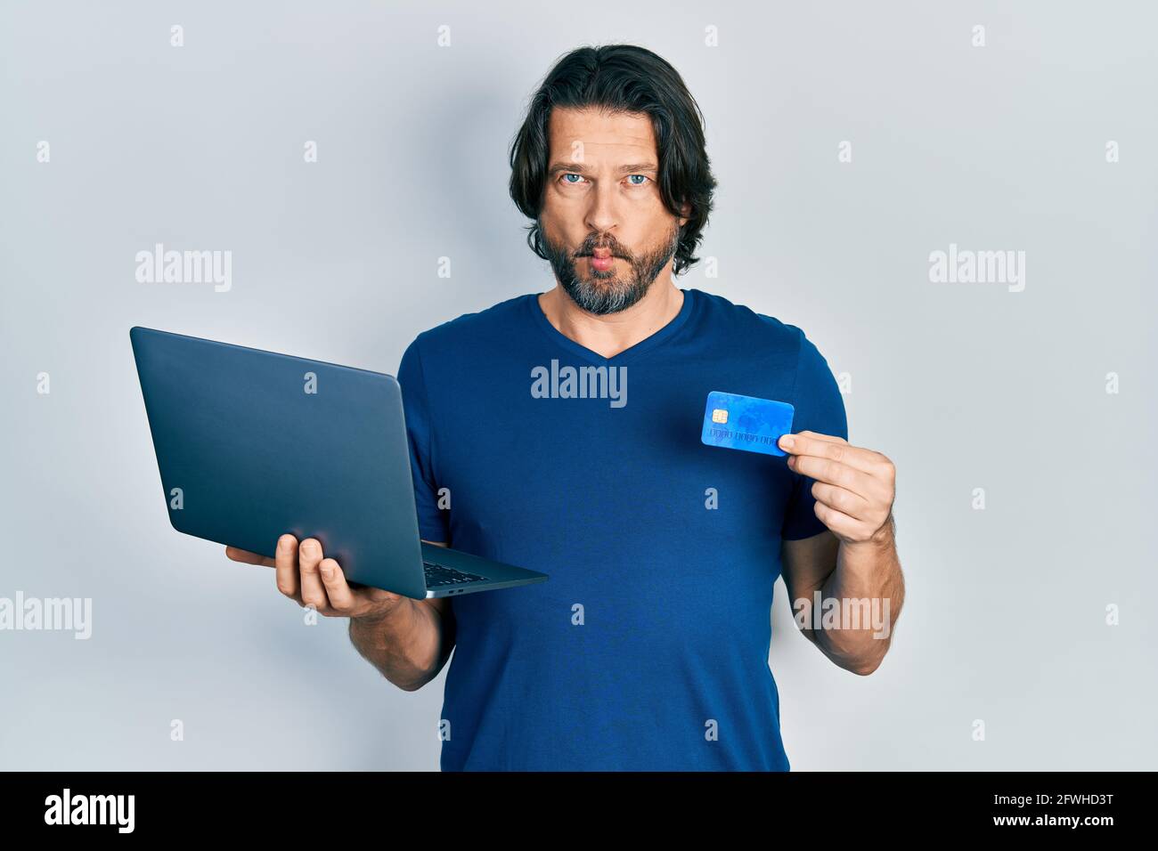 Middle age caucasian man wearing business style holding laptop and ...