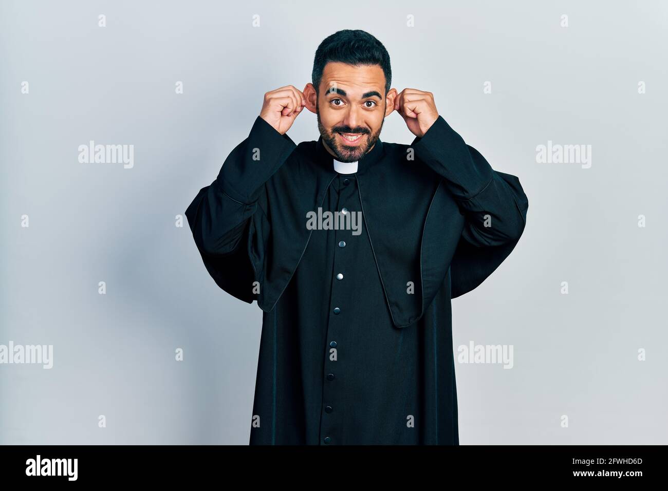 Handsome hispanic man with beard wearing catholic priest robe smiling ...