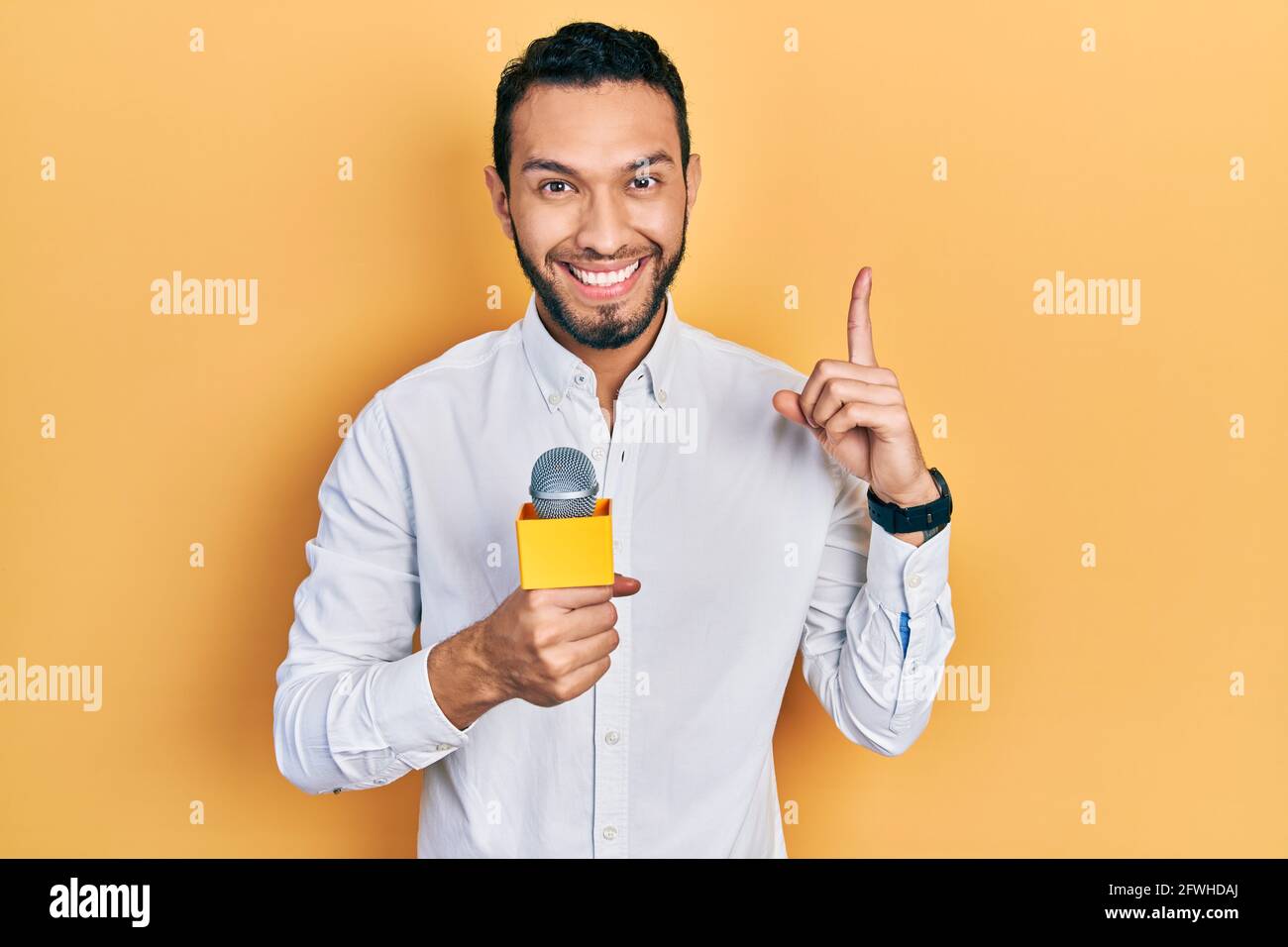 Hispanic man with beard holding reporter microphone surprised with an ...
