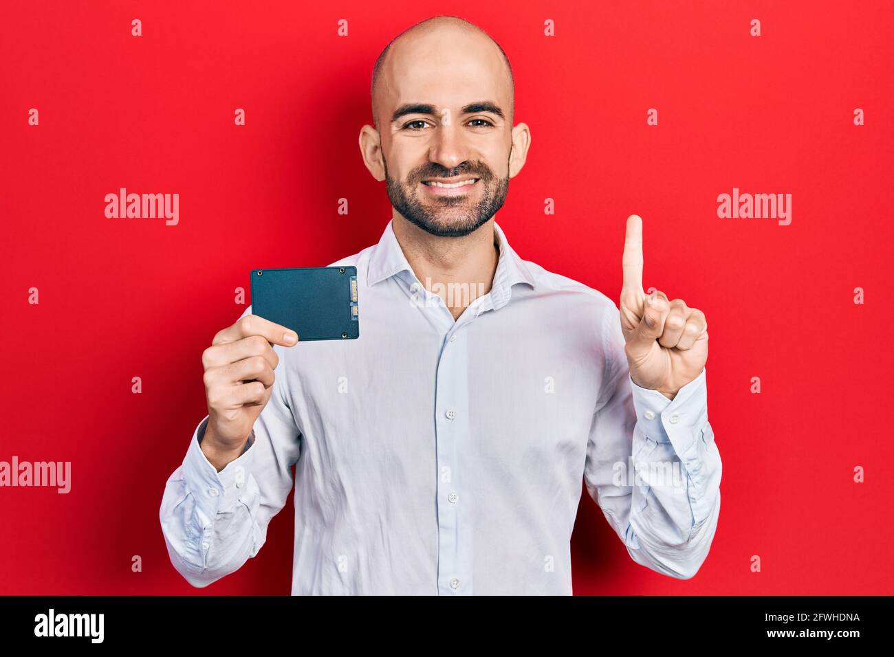 Young bald man holding ssd memory smiling with an idea or question ...