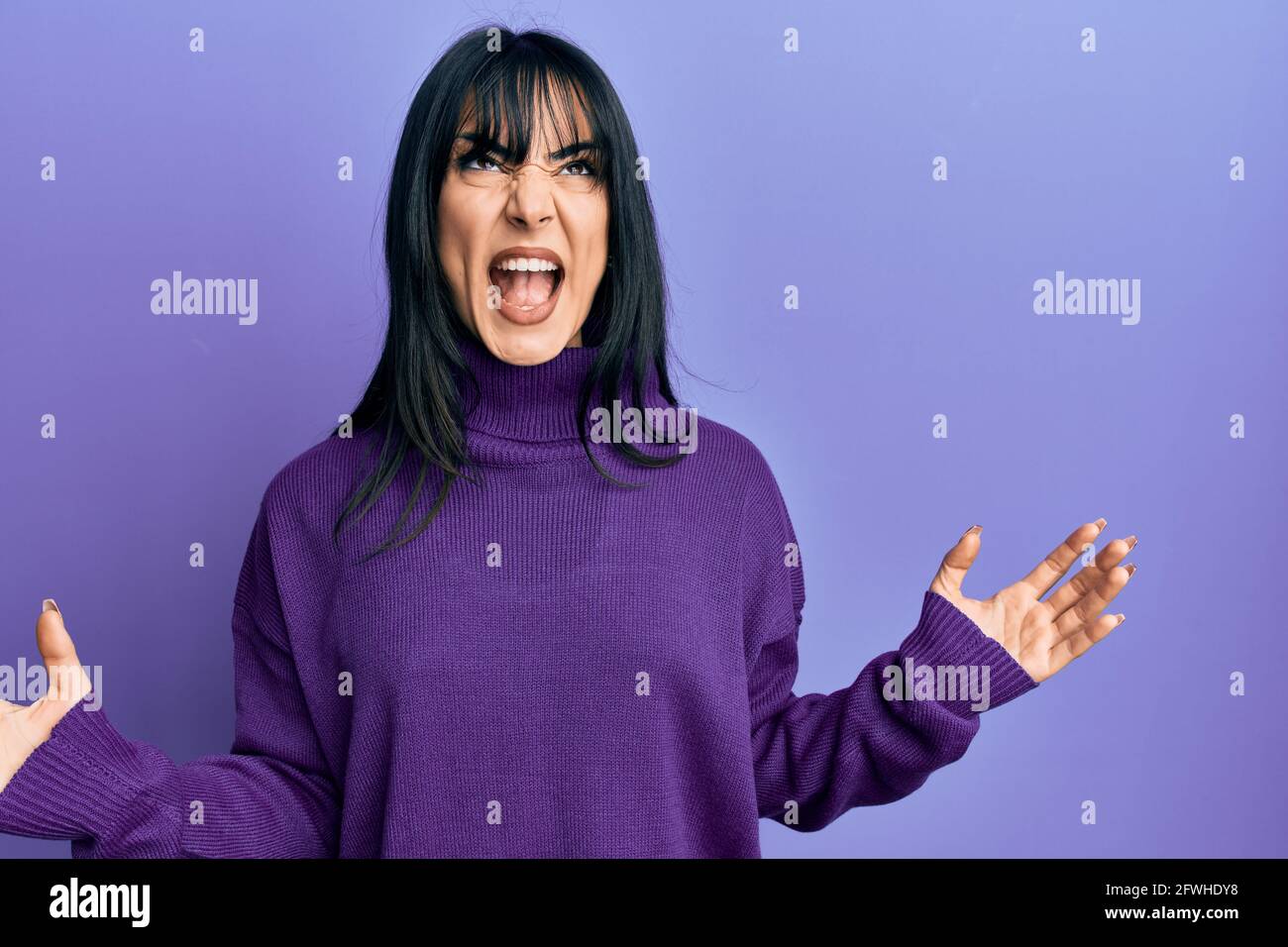 Young brunette woman with bangs wearing turtleneck sweater crazy and ...