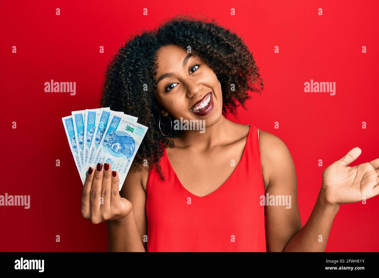 Beautiful african american woman with afro hair holding 50 polish zloty ...