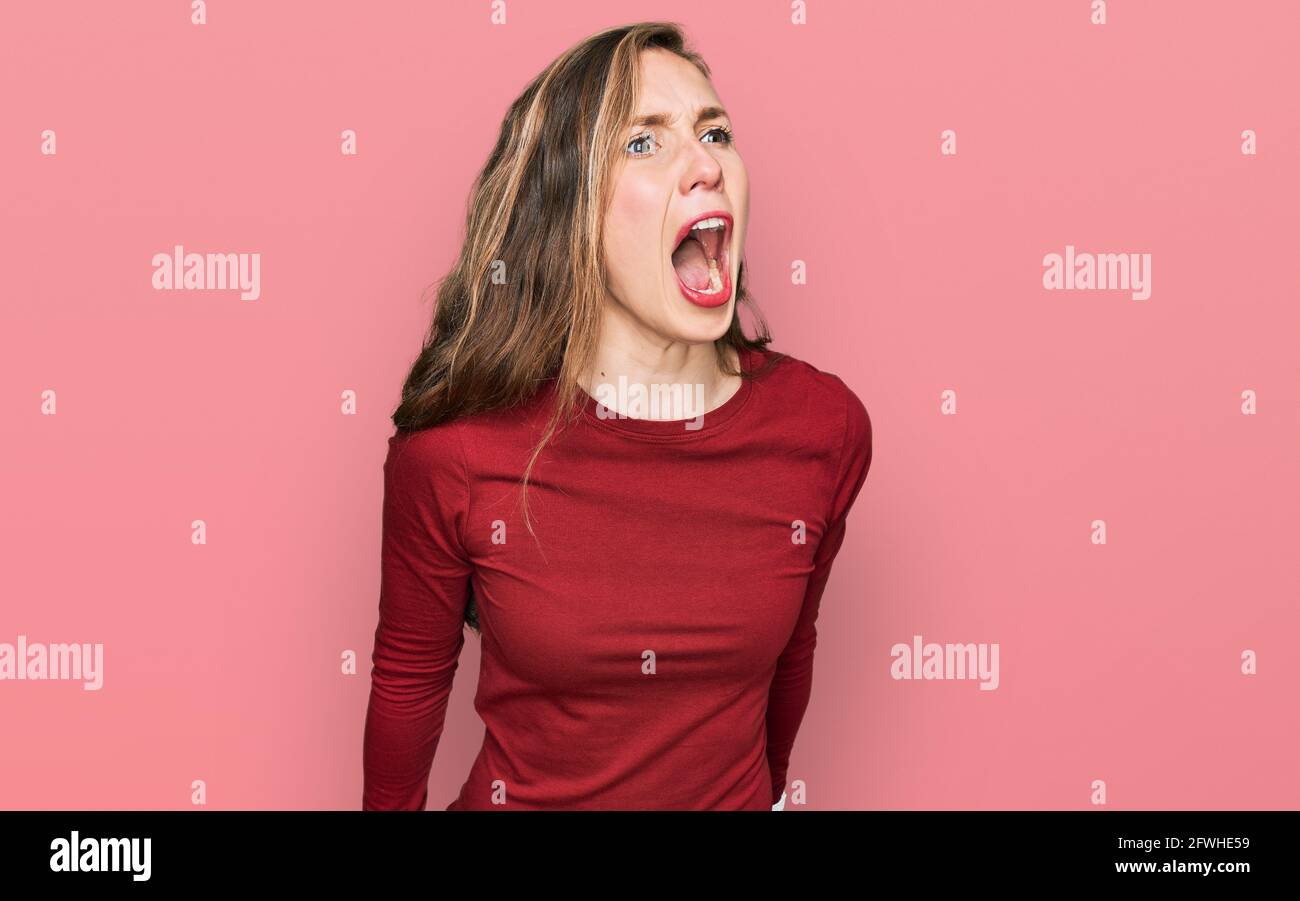 Young blonde woman wearing casual clothes angry and mad screaming ...