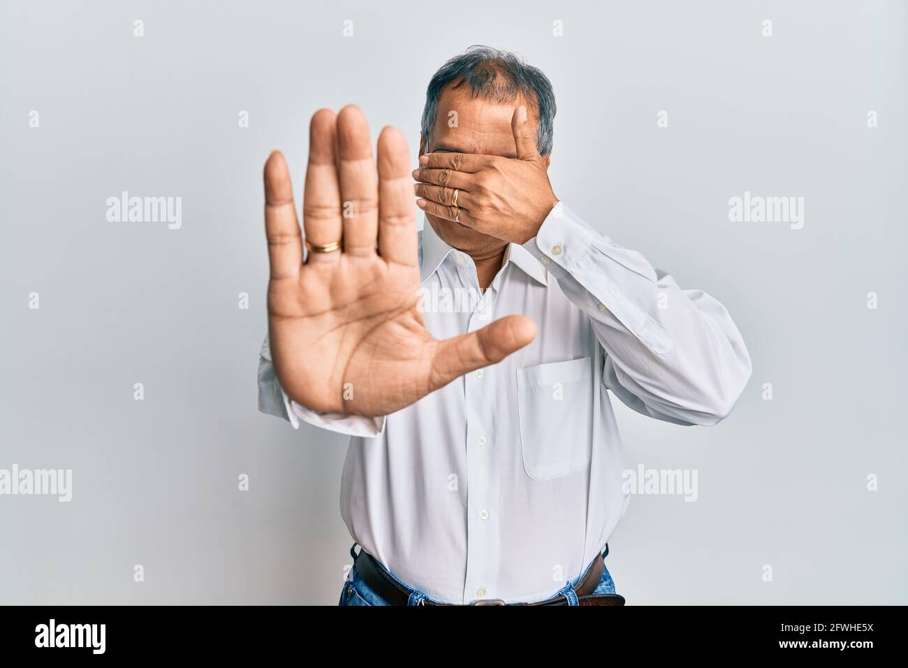 Middle age indian man wearing casual clothes and glasses covering eyes ...