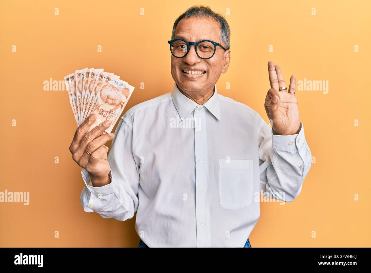 Middle age indian man holding 50 turkish lira banknotes doing ok sign ...
